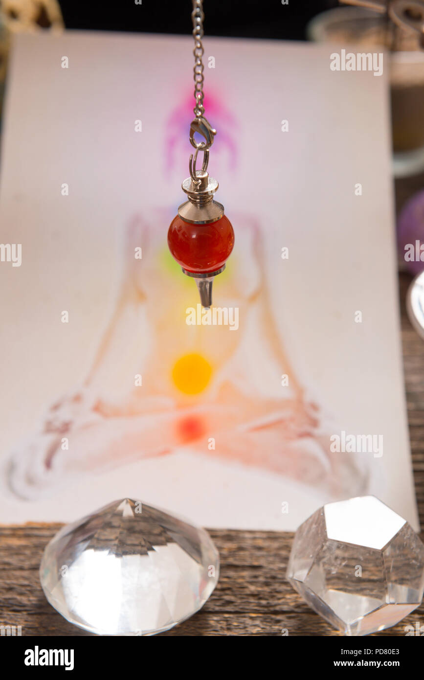 Chakras illustrated over human body with natural crystals and pendulum ...