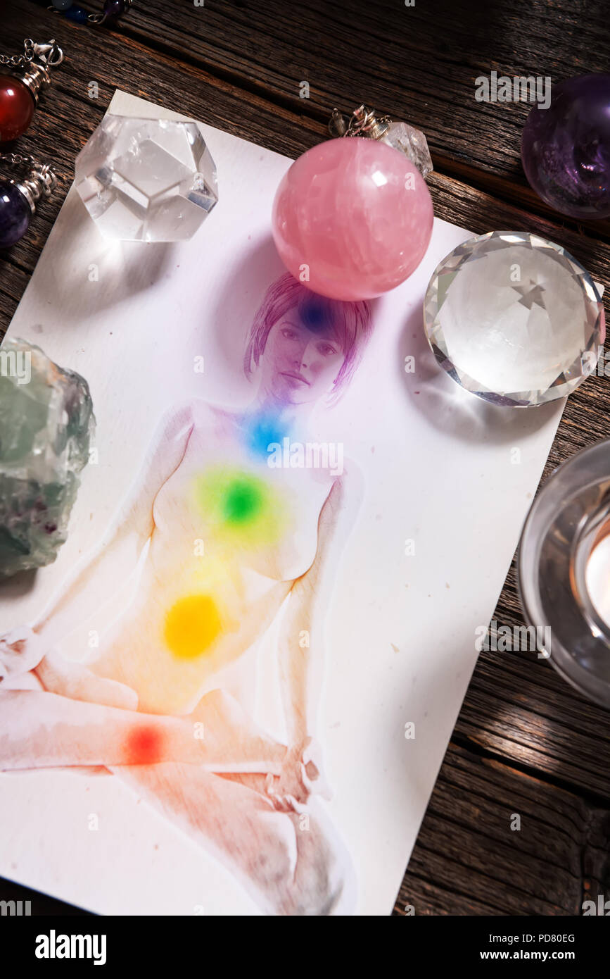 Chakras illustrated over human body with natural crystals and pendulum ...