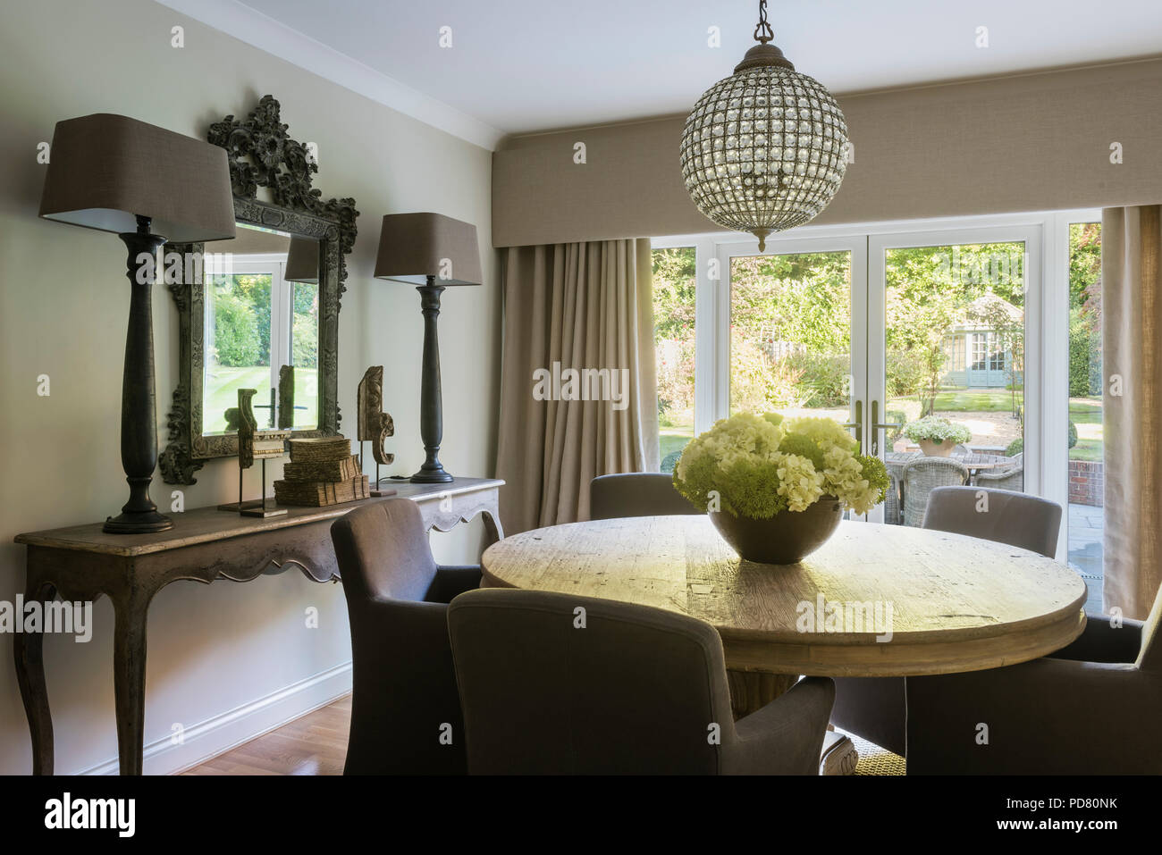 Round crystal-effect chandelier by Artisanti above round wooden dining ...