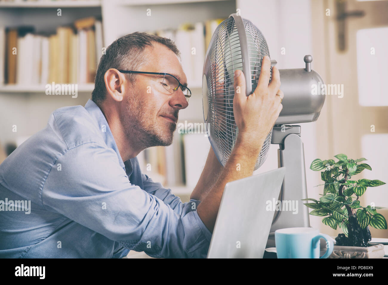Man suffers from heat while working in the office and tries to cool off ...