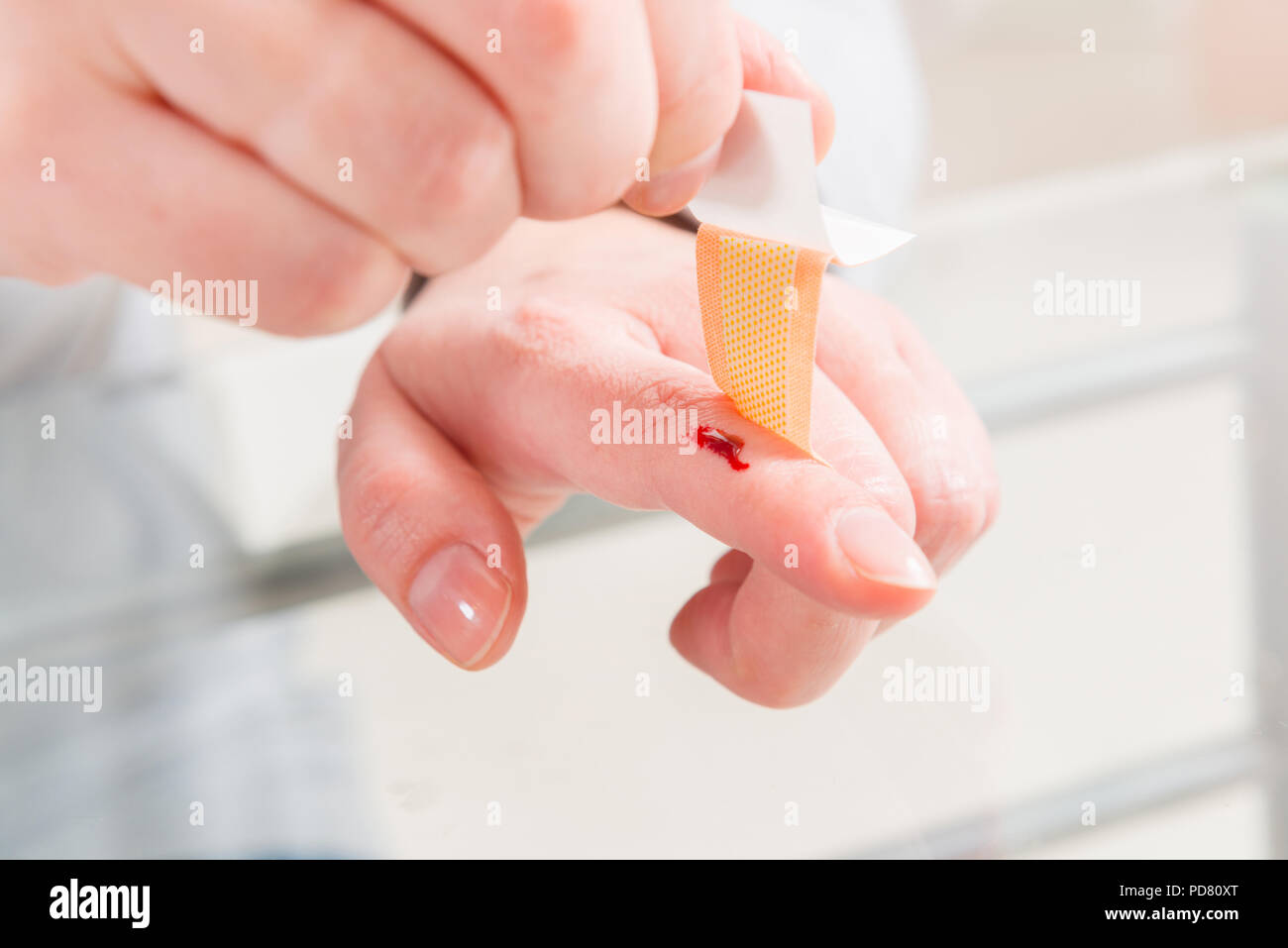 Applying adhesive bandage on bleeding finger Stock Photo - Alamy