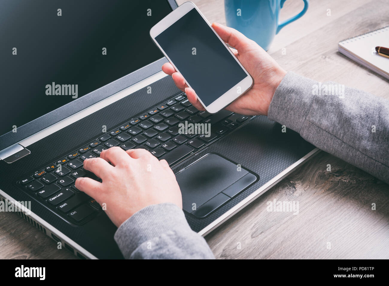 Concept of modern working style. Hand holding smartphone and other one ...