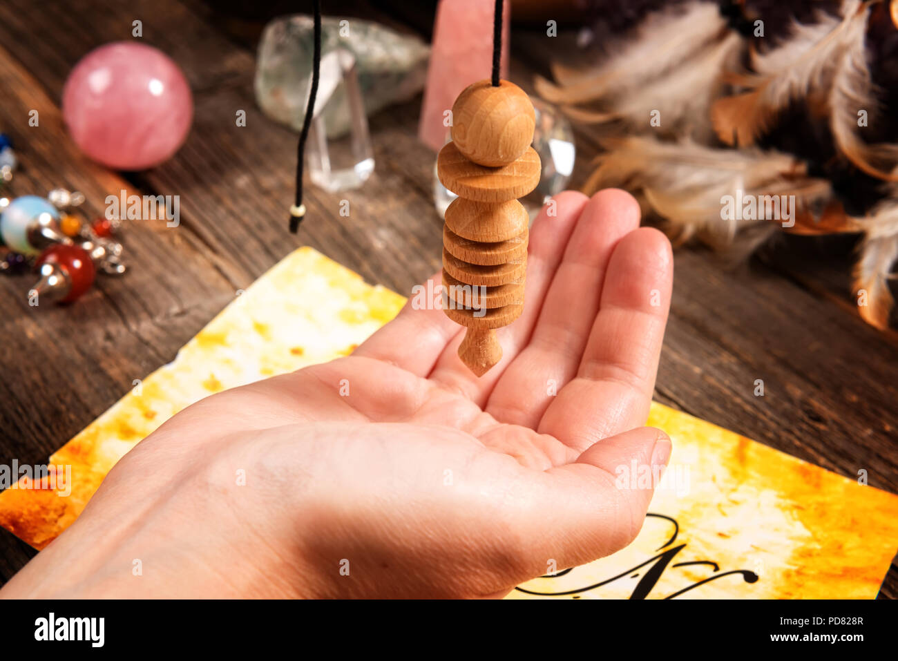 Pendulum, tool for dowsing, over a hand Stock Photo - Alamy