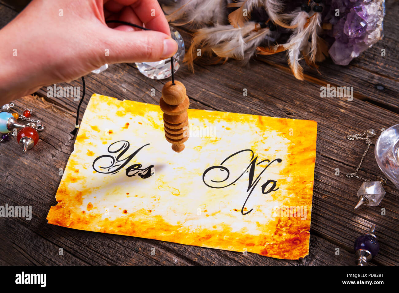 Pendulum, tool for dowsing in hand, over yes and no choosing diagram ...