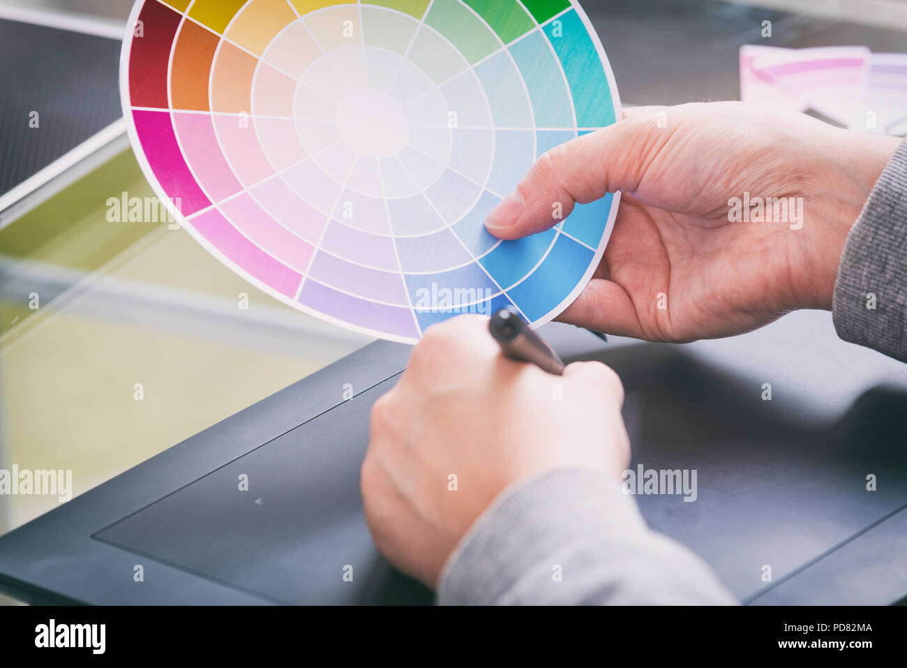 Designer using graphics tablet and holdnig color wheel in the office ...