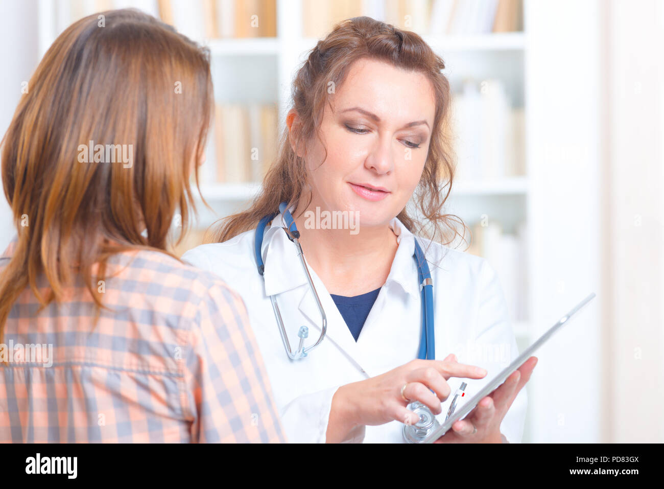 Medical doctor holding tablet and talking with her patient in the ...