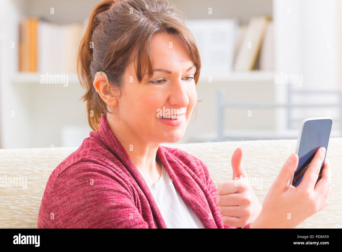 Smiling Deaf woman talking using sign language on the smartphone's cam ...
