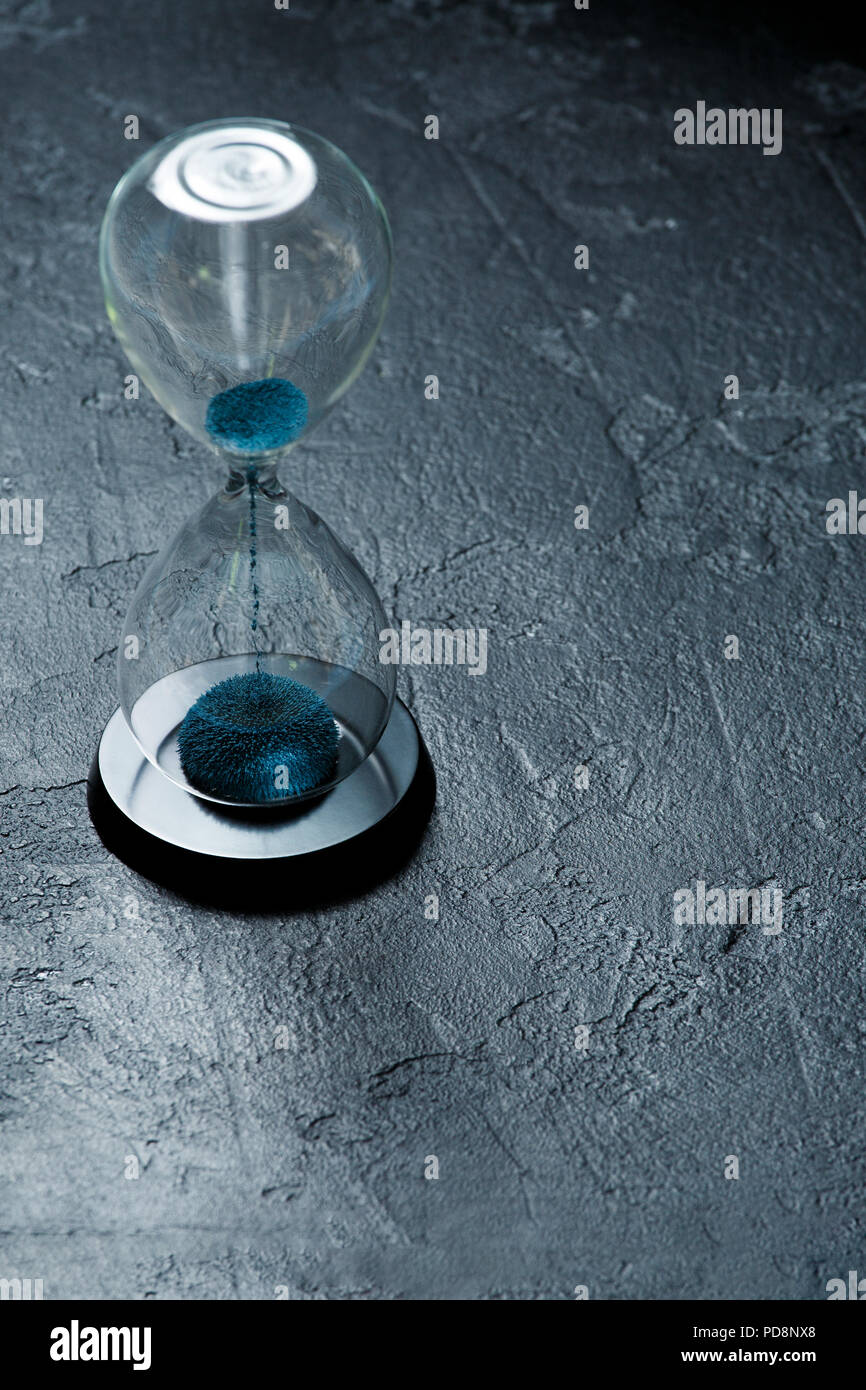 Photo of hourglass with blue sand on black stone background Stock Photo ...