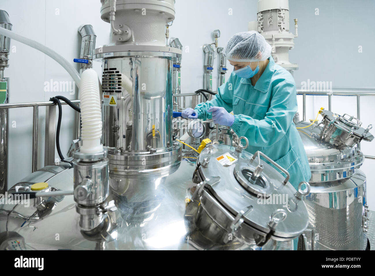 Pharmaceutical factory woman worker in protective clothing operating ...