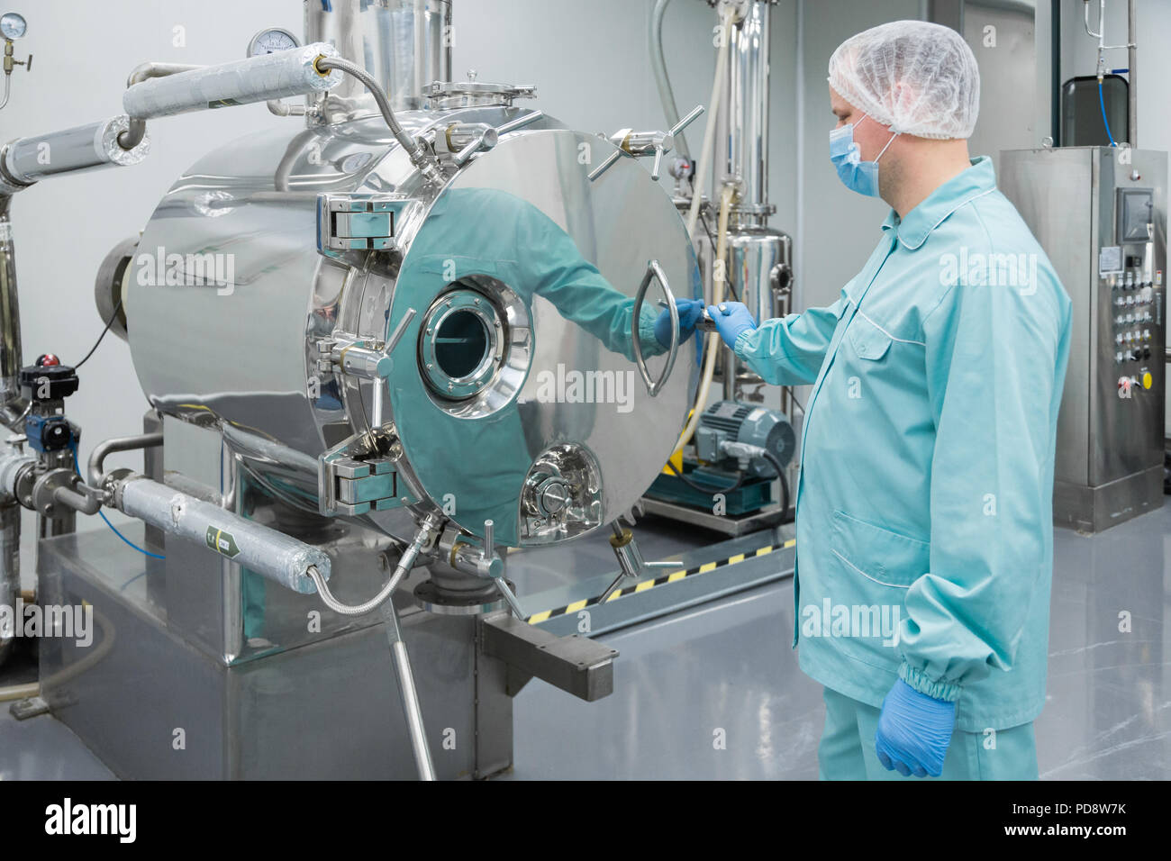 Pharmaceutical factory man worker in protective clothing working on ...