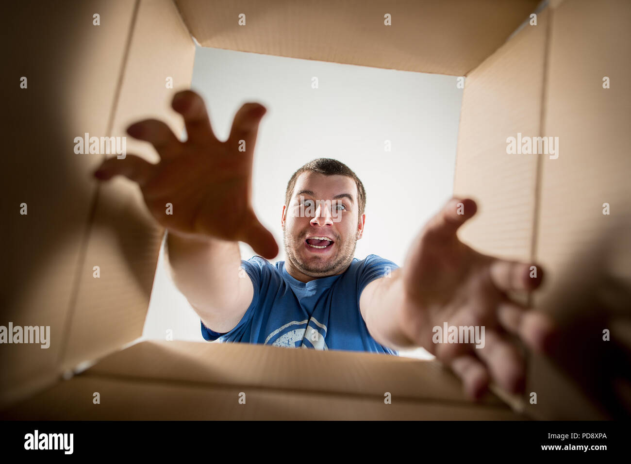 The surprised man unpacking, opening carton box and looking inside. The ...