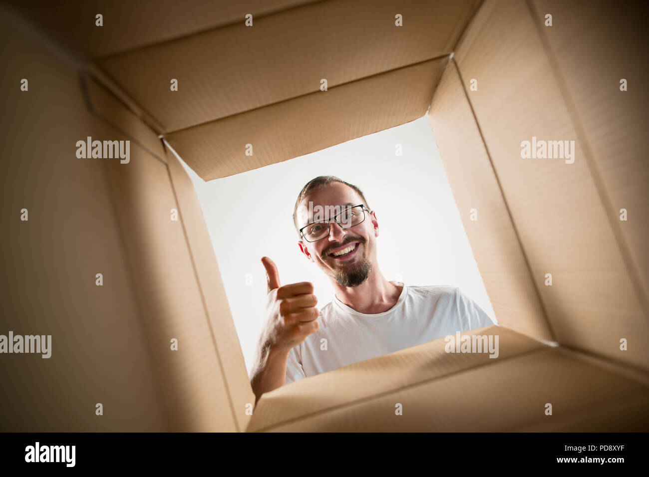 The surprised man unpacking, opening carton box and looking inside. The ...