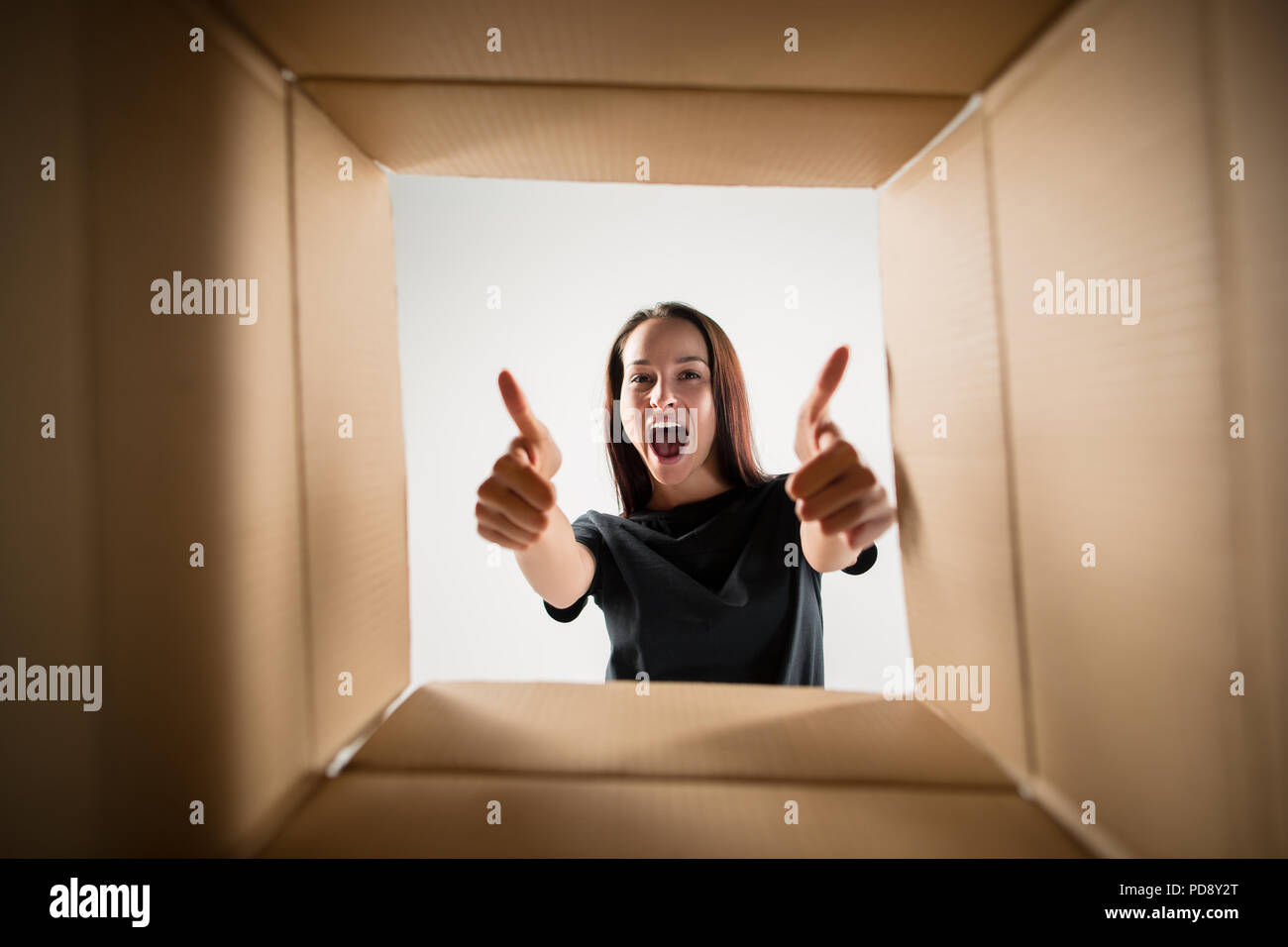 The surprised woman unpacking, opening carton box and looking inside ...
