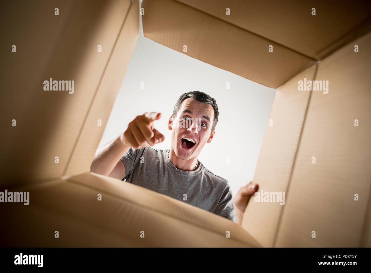 The surprised man unpacking, opening carton box and looking inside. The ...