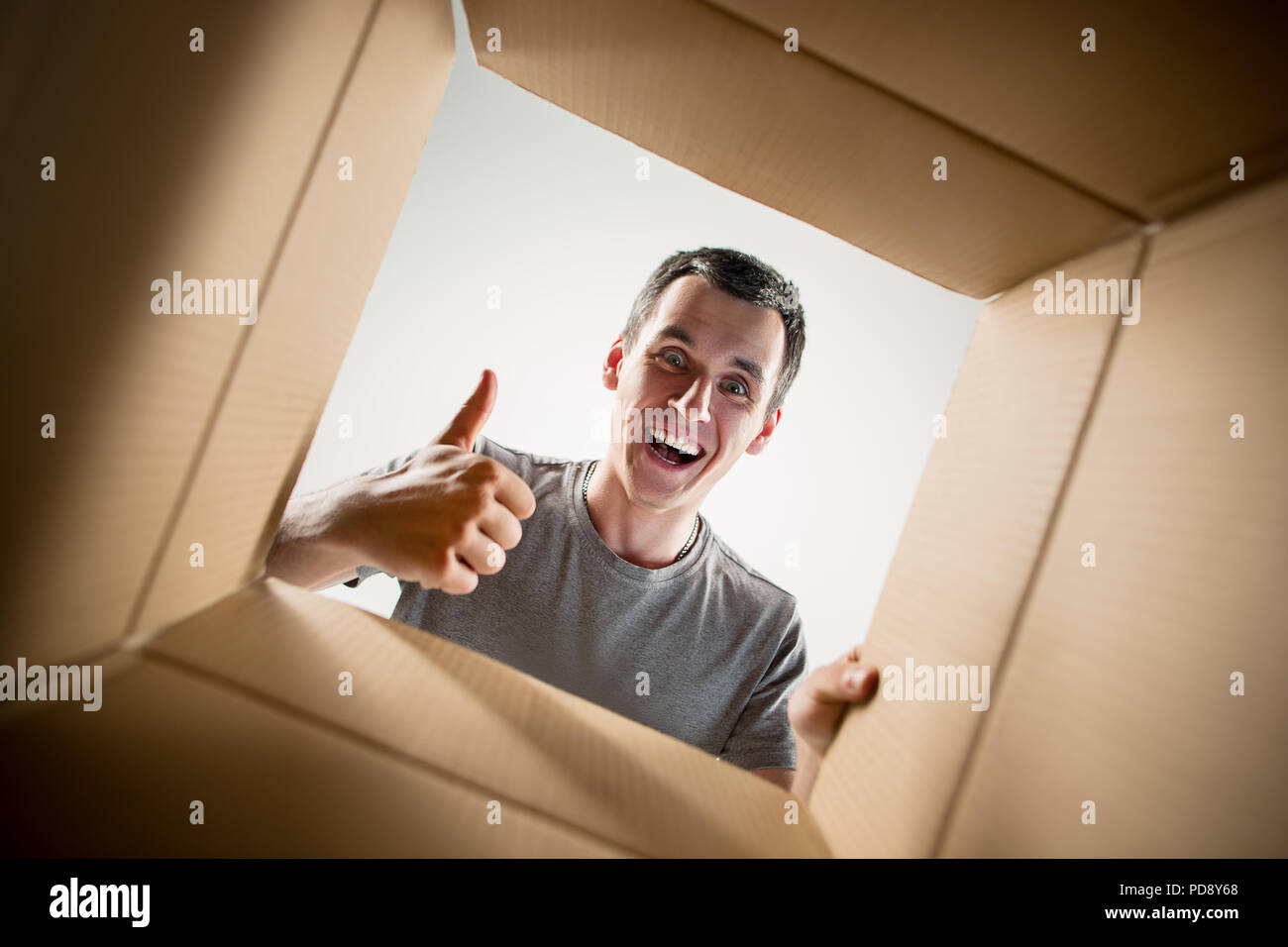 The surprised man unpacking, opening carton box and looking inside. The ...