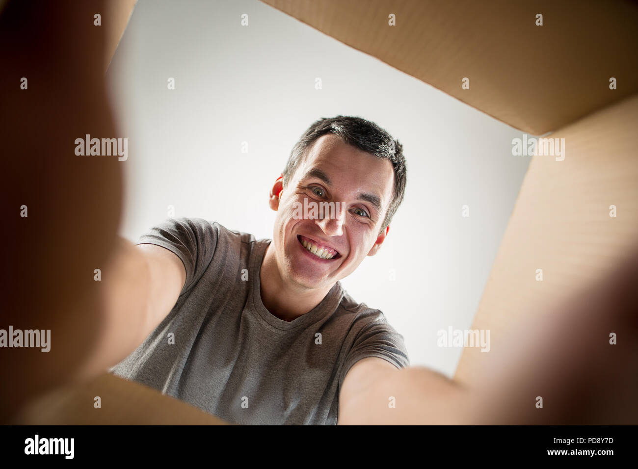 The surprised man unpacking, opening carton box and looking inside. The ...