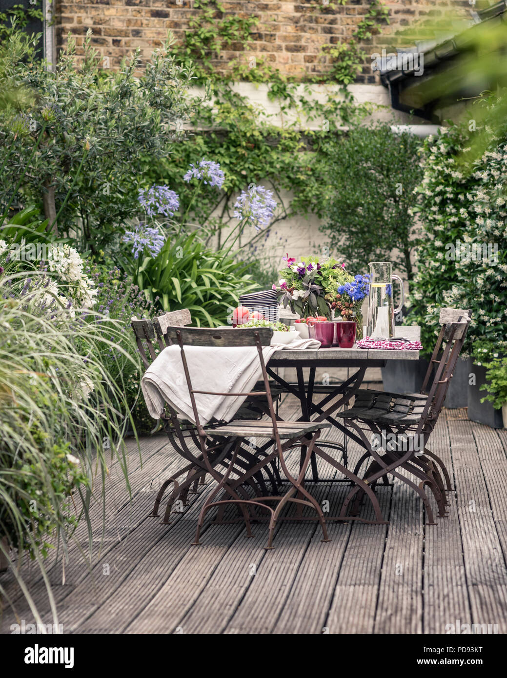 Old French bistro chairs around long wooden table on garden roof ...