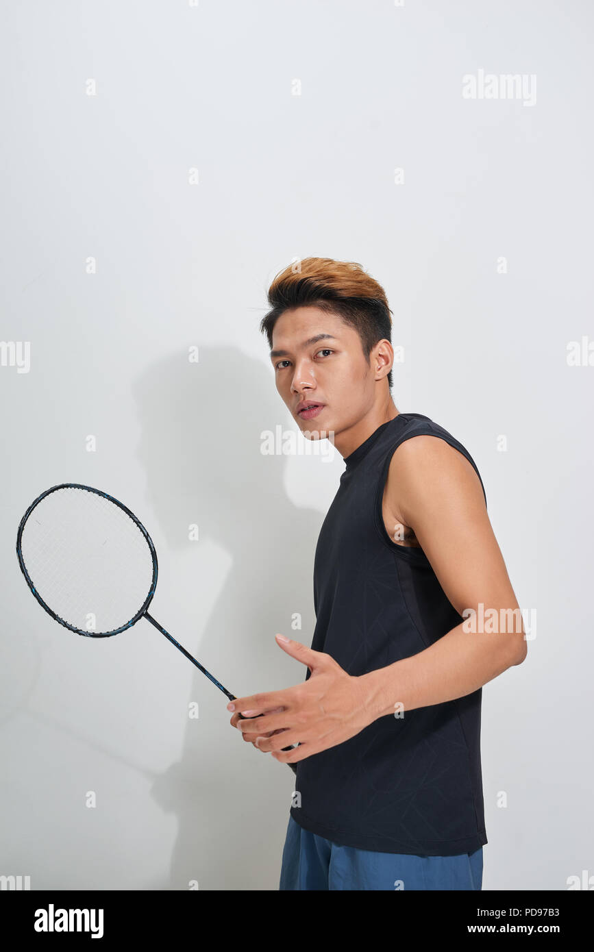 handsome young man holding badminton racket and shuttlecock on gray ...