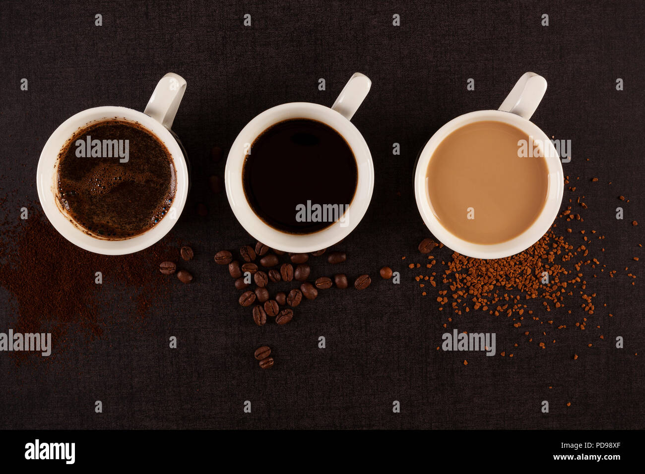 Three cups of coffe with ground, instant coffee and roasted beans on ...