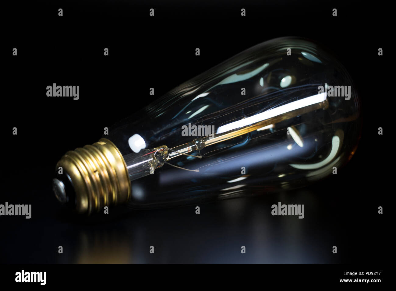 Light bulb on a black reflective surface. Close up of a light with tiny ...