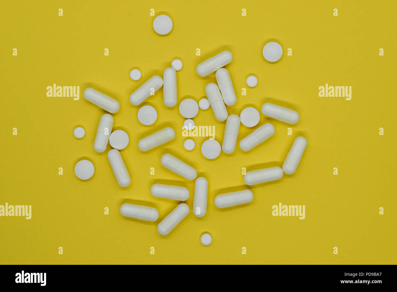 Bunch of different forms white medication pills on yellow background ...