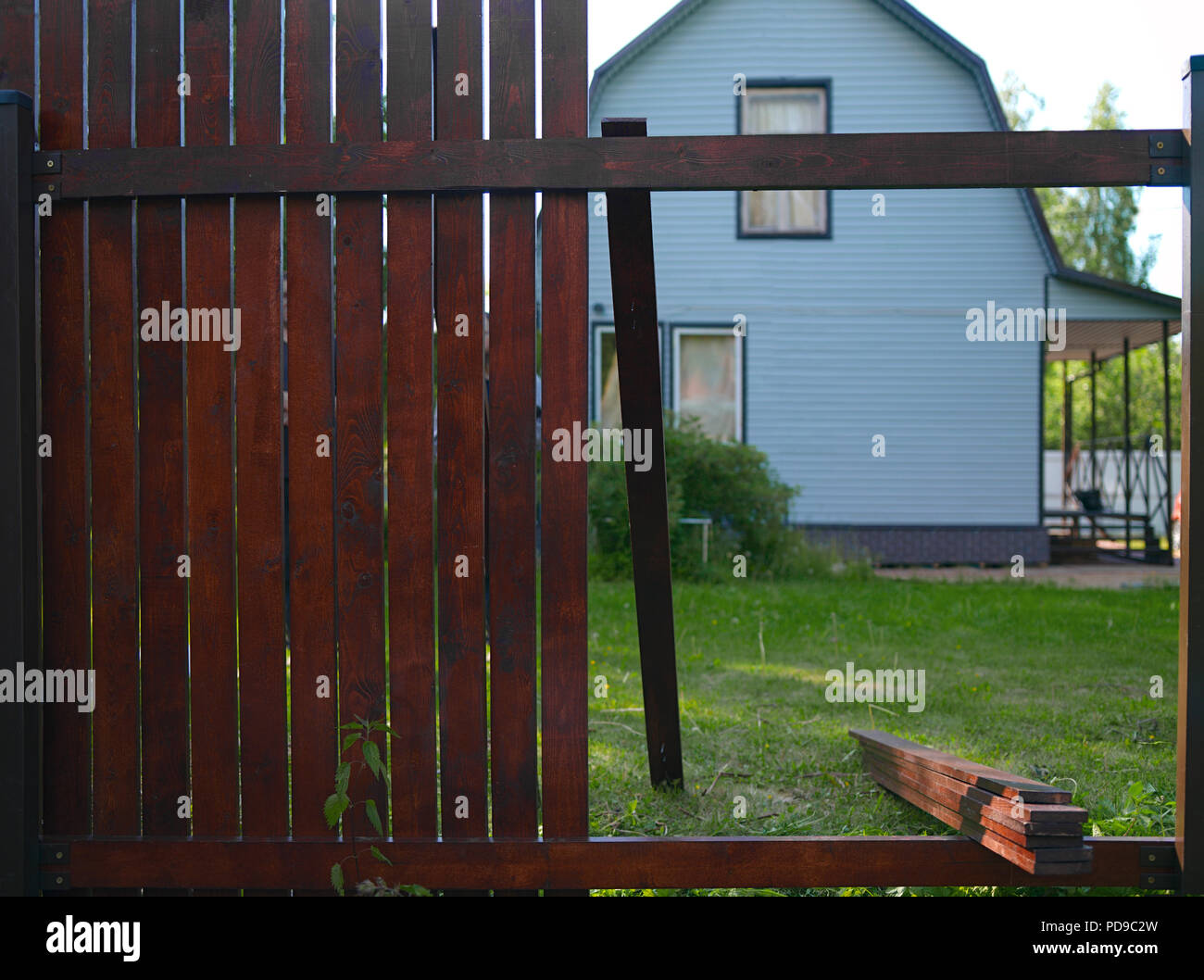 Unfinished wooden fence and a house in the background Stock Photo - Alamy