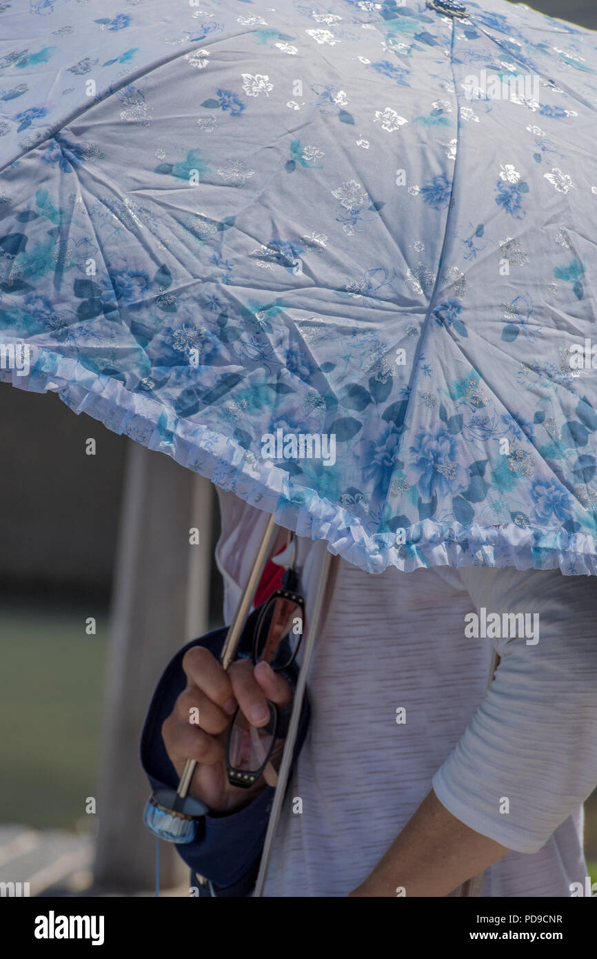 woman holding an umbrella with her face hidden underneath the brollie ...