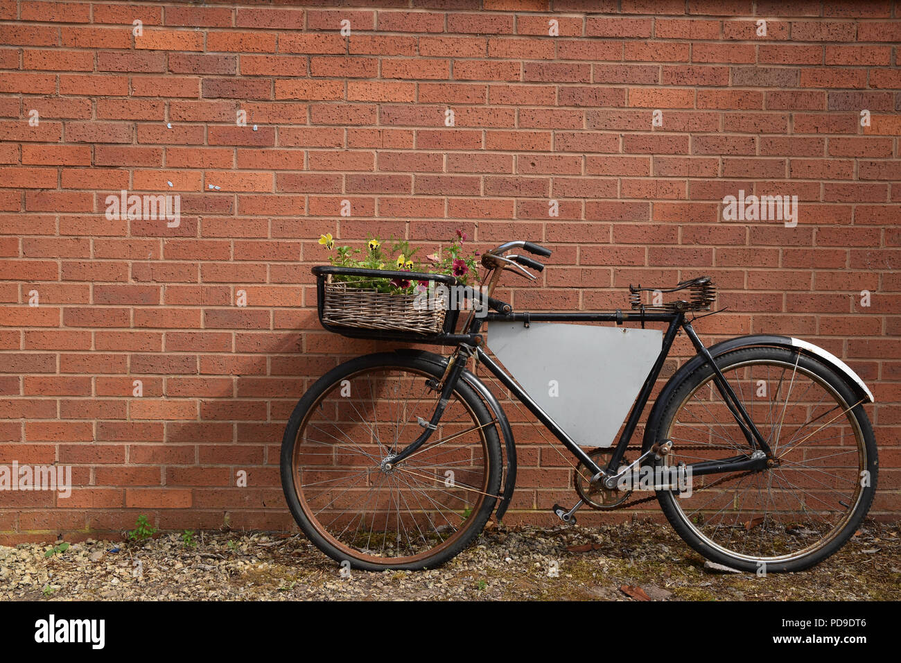 Rusty old fashioned merchant’s bicycle leaning against a red brick wall ...