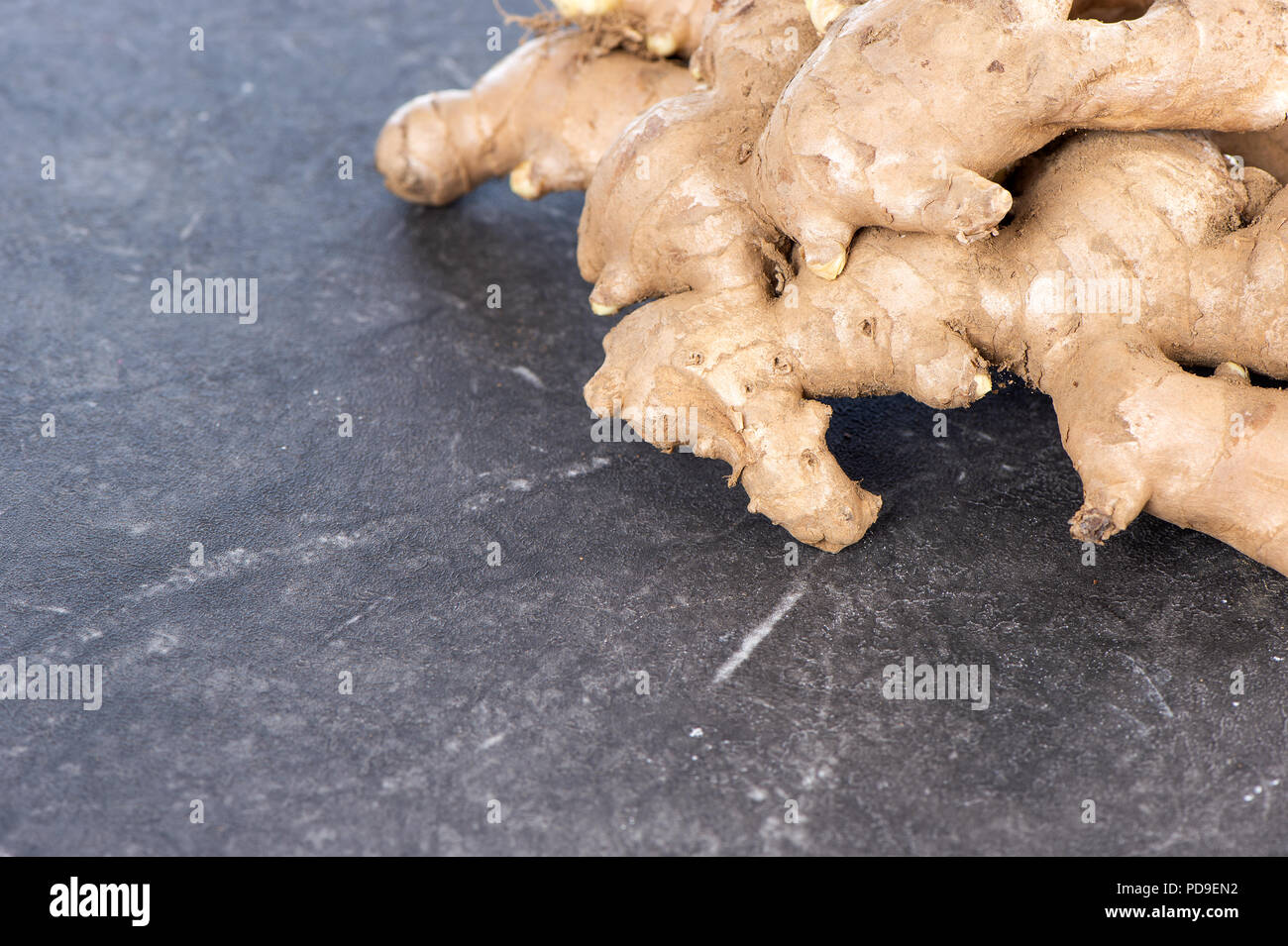 Whole ginger roots on dark old stone background table, space for text ...