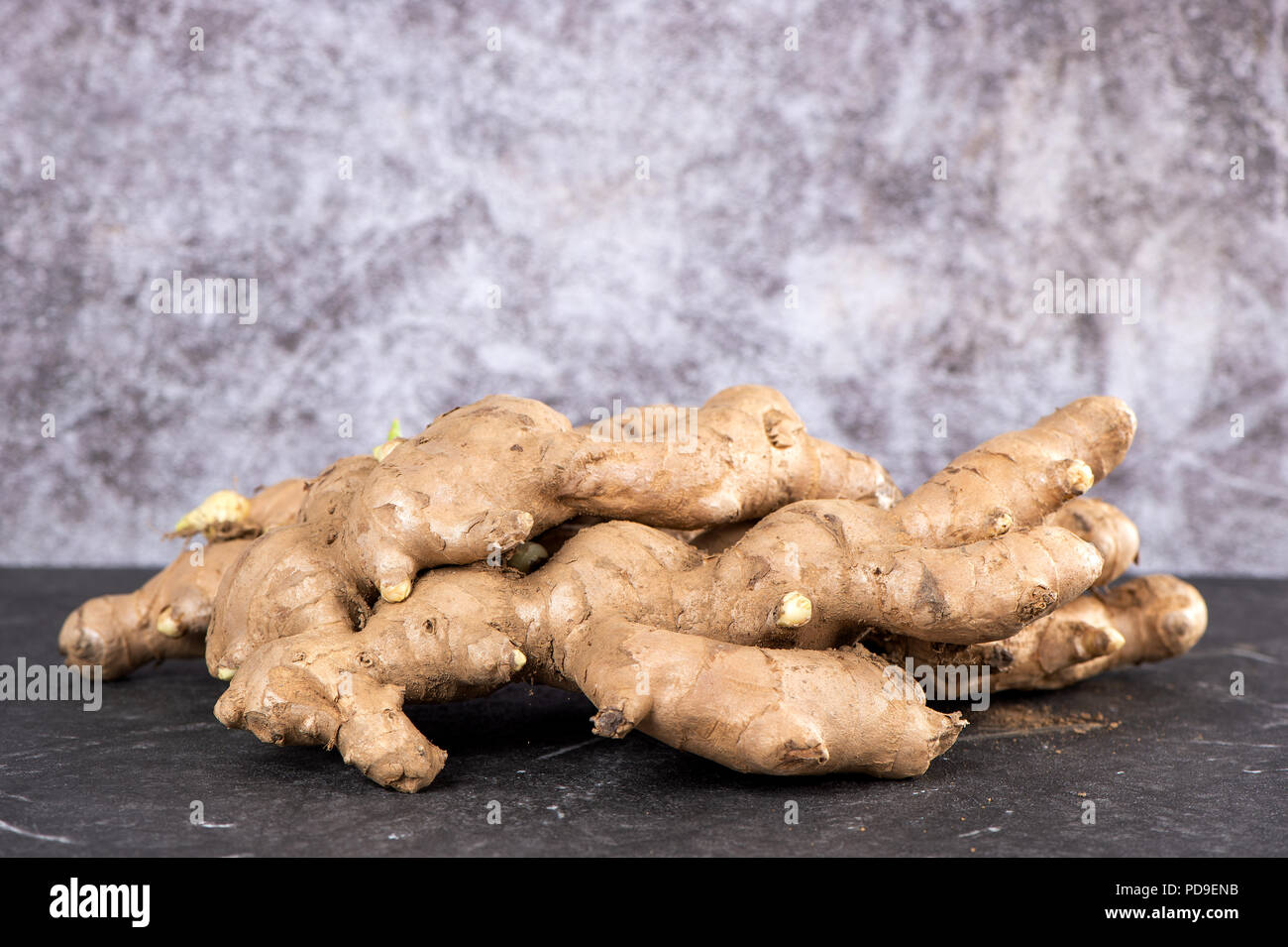 Whole ginger roots on dark old stone background table, space for text ...