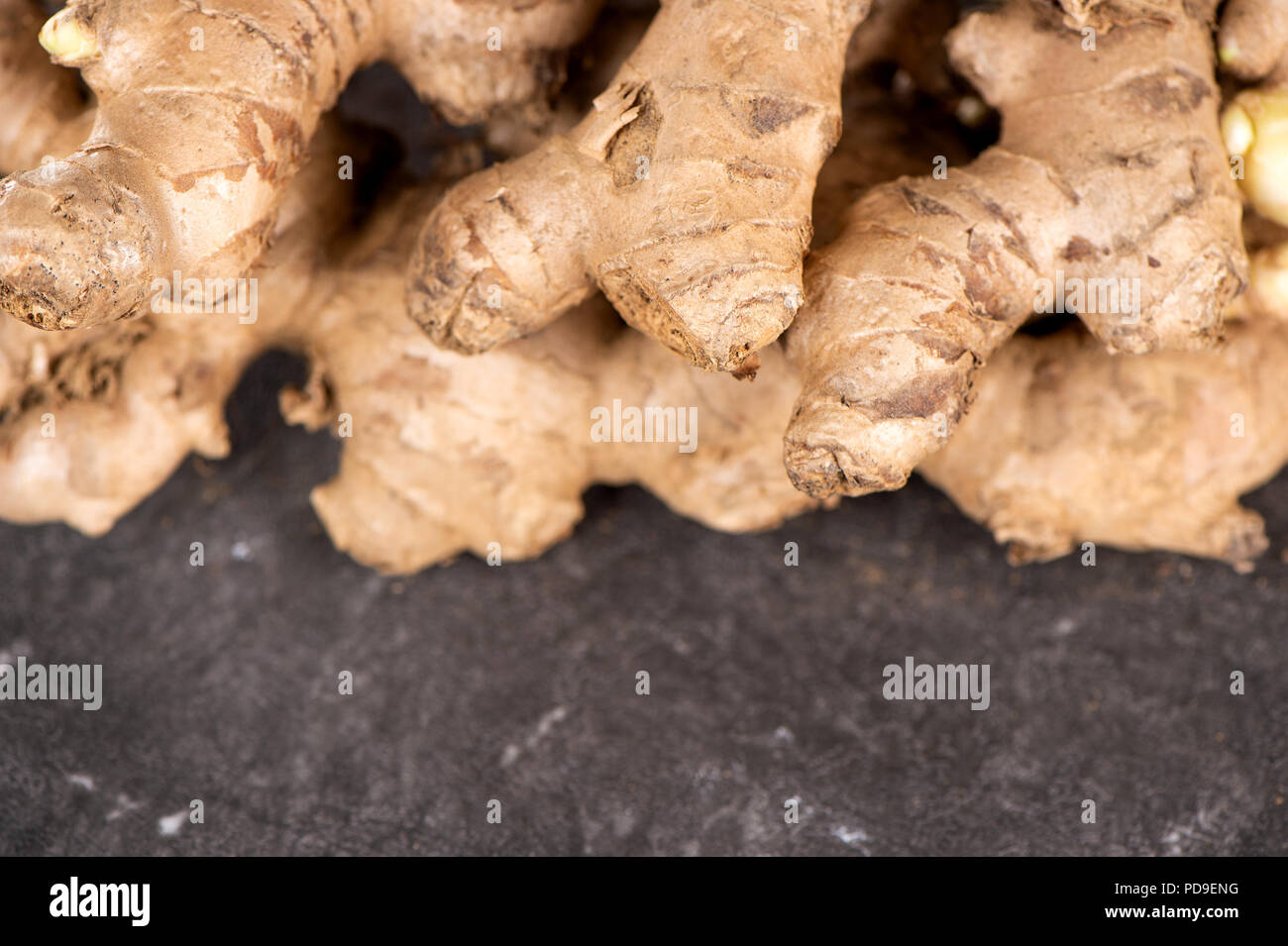 Whole ginger roots on dark old stone background table top view space ...