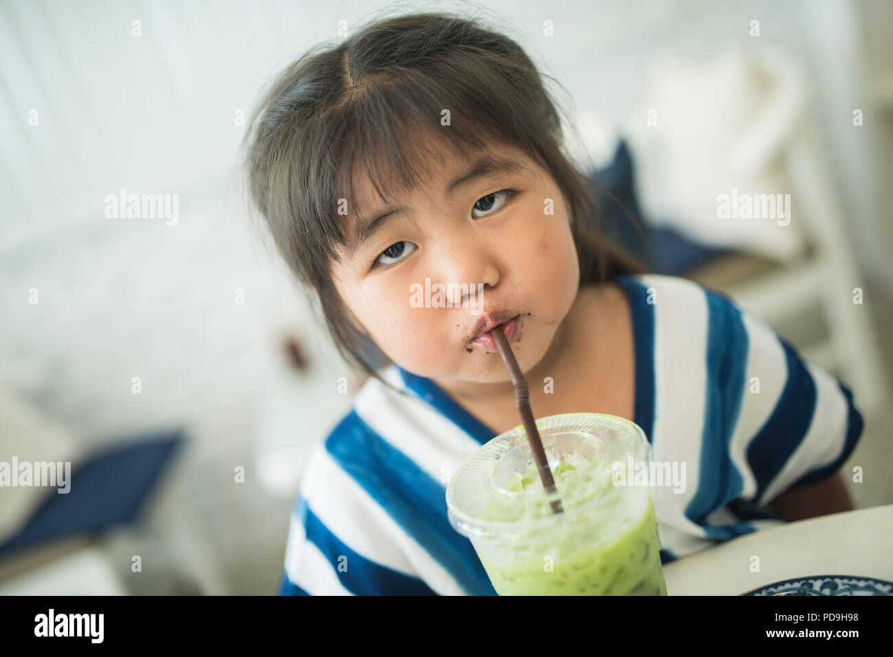 A cute asian girl drinking green tea with funny face Stock Photo - Alamy