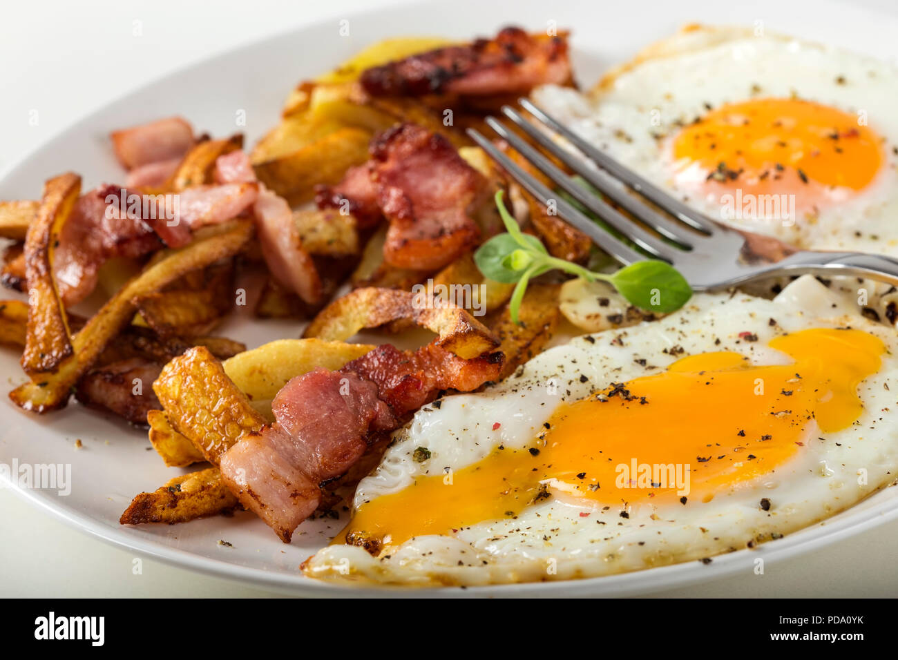 Homemade eggs with French fries and fried bacon on plate - close up ...