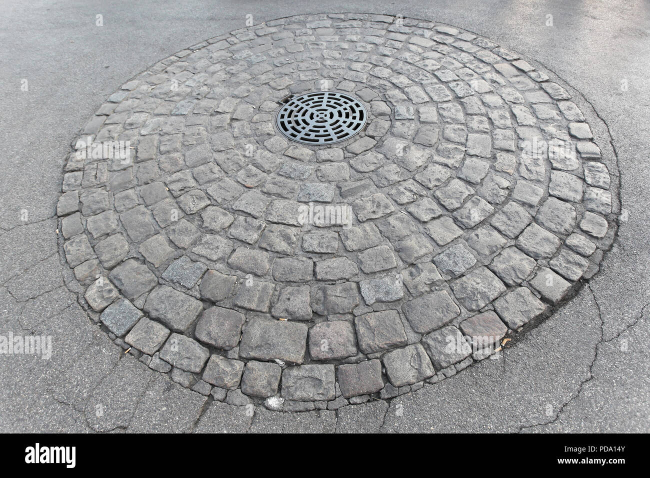 Manhole with drainage sewerage in cobblestone circle Stock Photo - Alamy