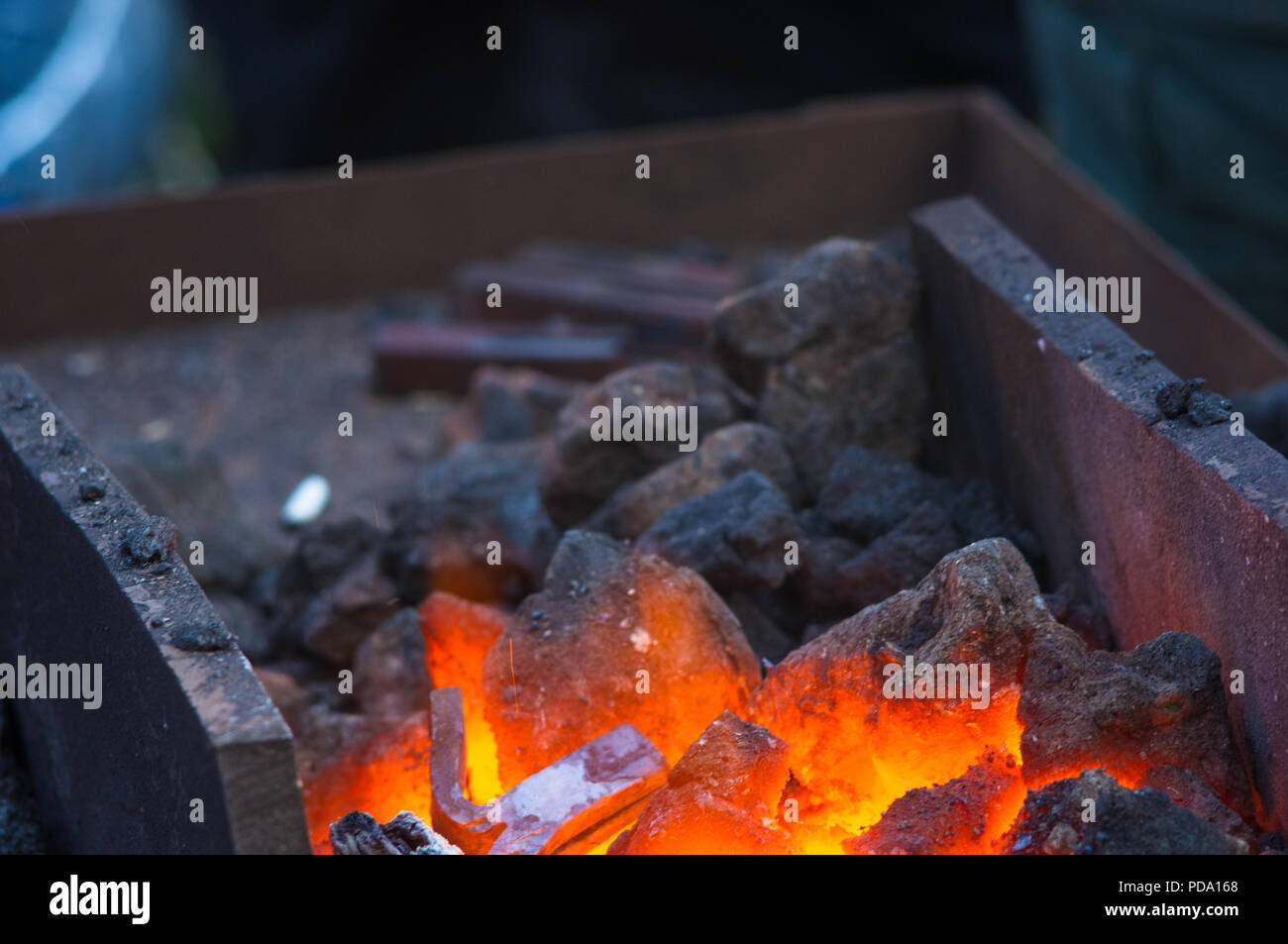 blacksmith performs the forging of hot glowing metal on the anvil ...