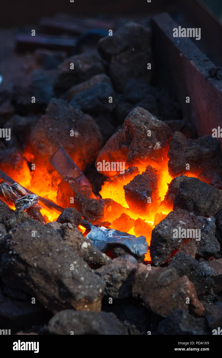 blacksmith performs the forging of hot glowing metal on the anvil ...