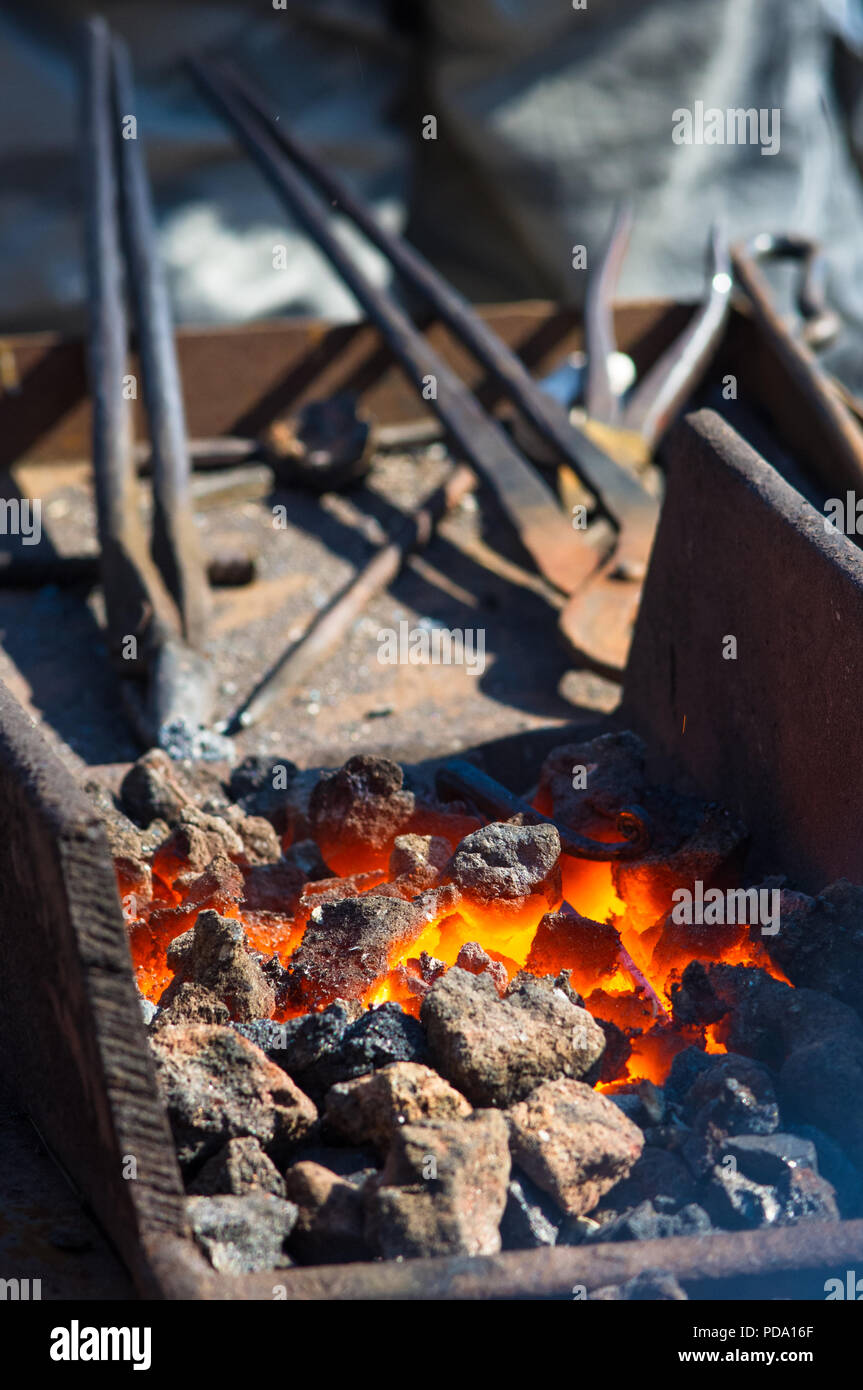 blacksmith performs the forging of hot glowing metal on the anvil ...