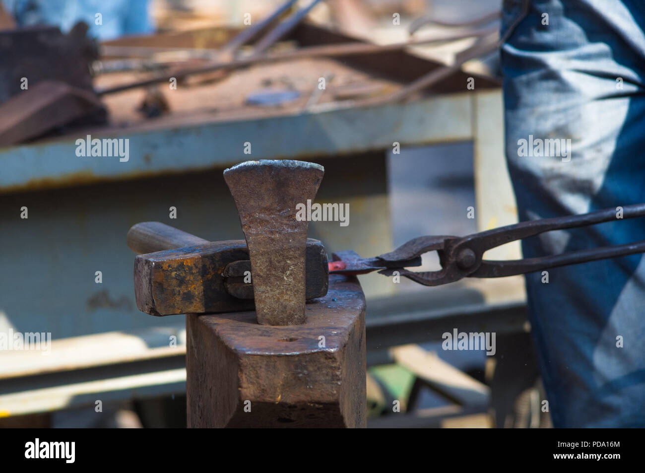 blacksmith performs the forging of hot glowing metal on the anvil ...