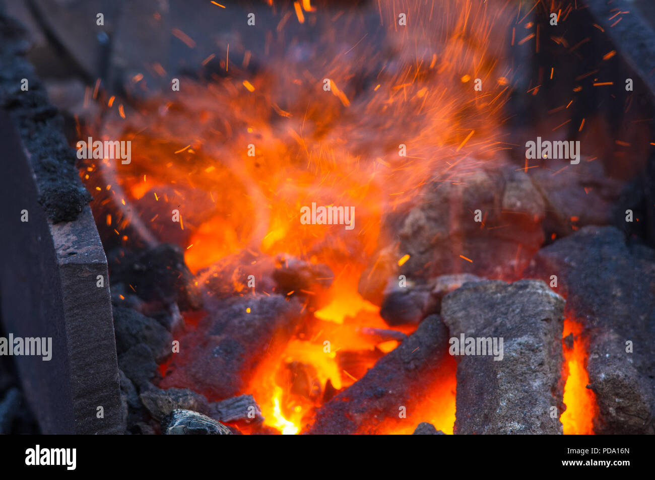 blacksmith performs the forging of hot glowing metal on the anvil ...