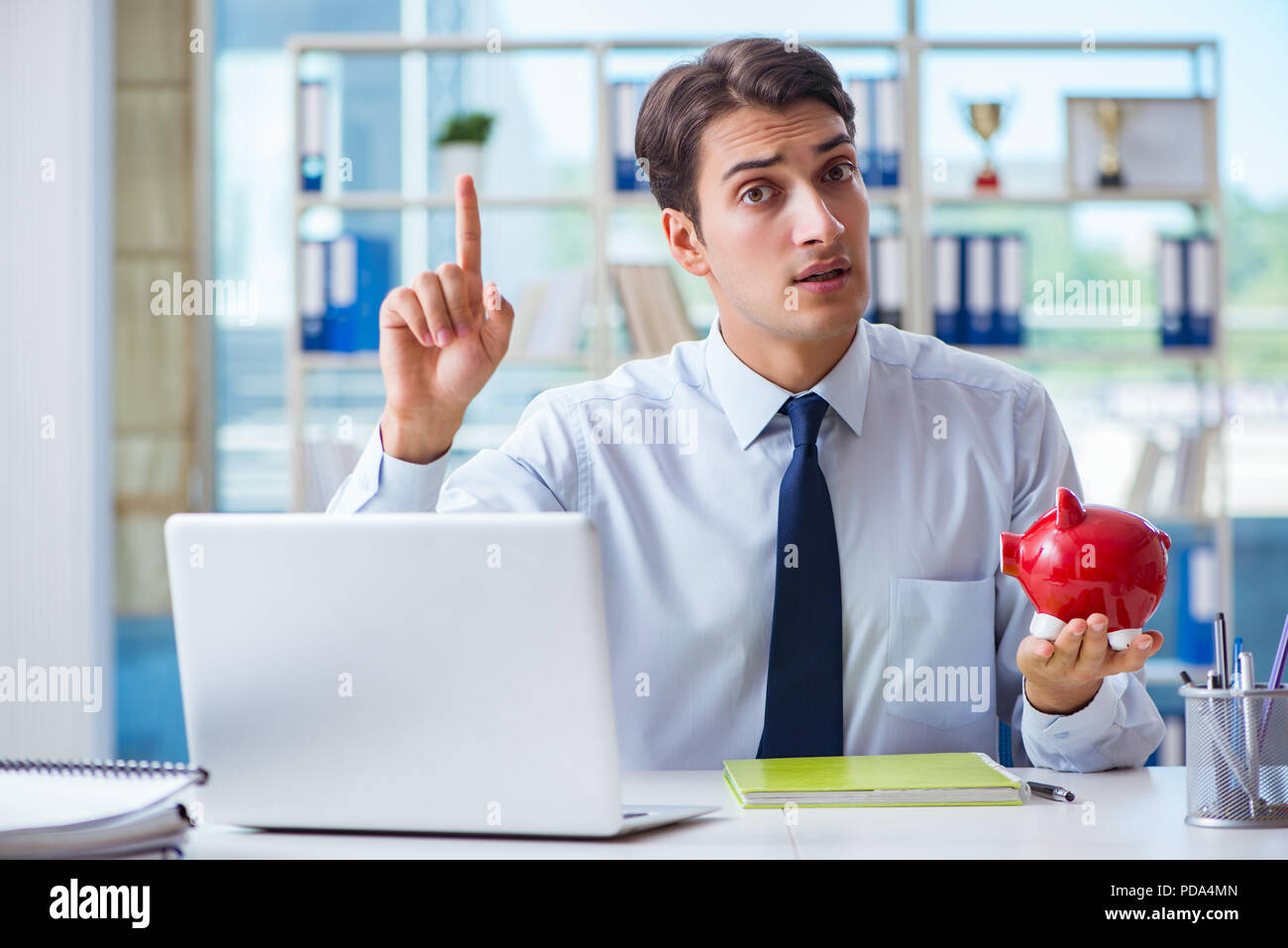 Businessman with piggy bank working in the office Stock Photo - Alamy