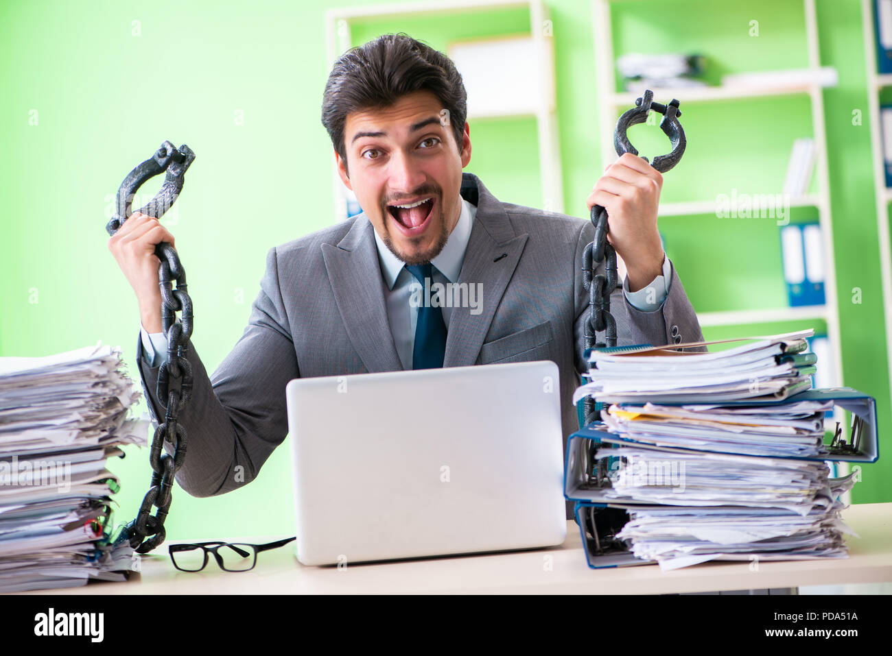 Employee chained to his desk due to workload Stock Photo - Alamy