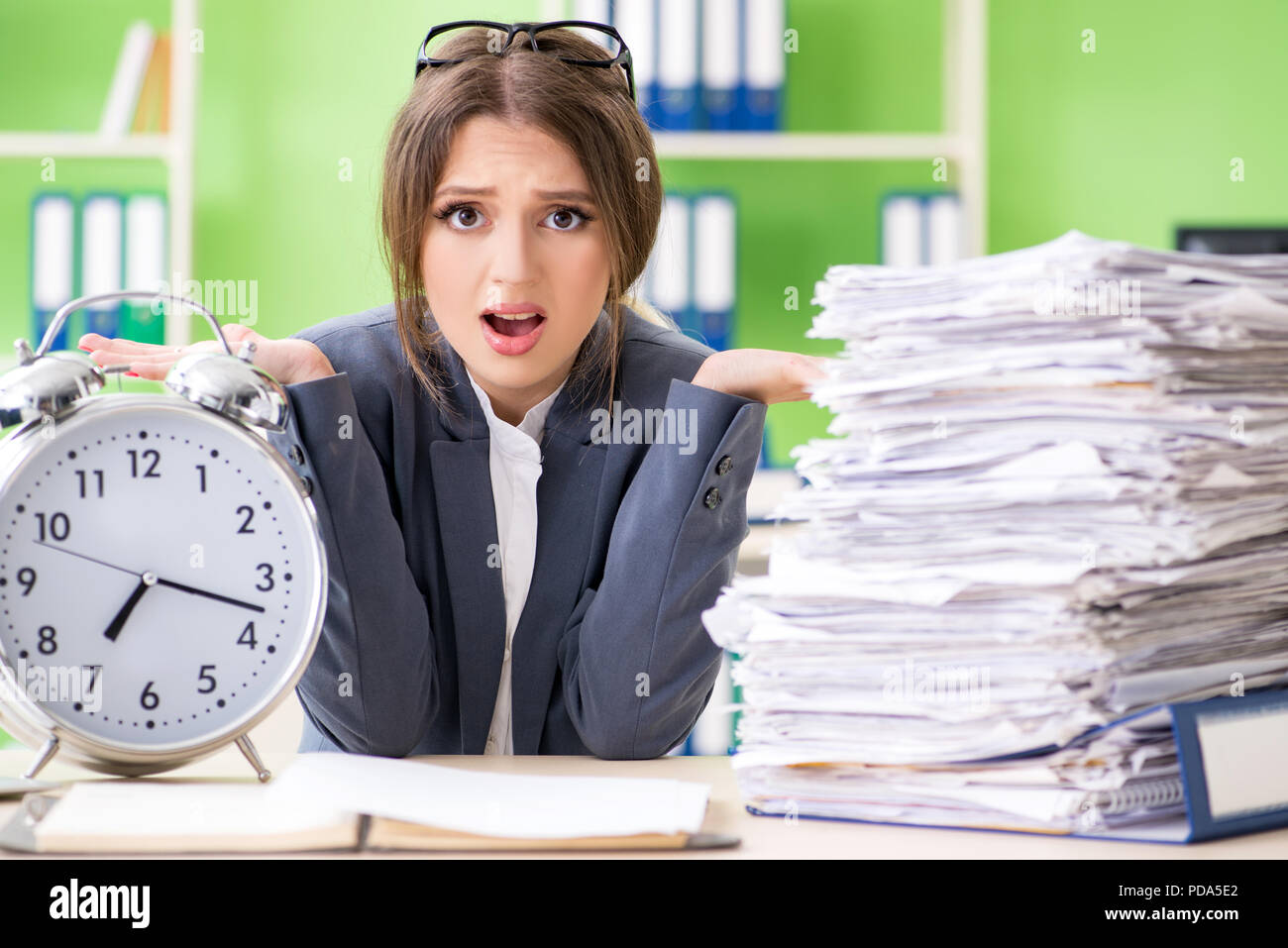 Young female employee very busy with ongoing paperwork in time ...