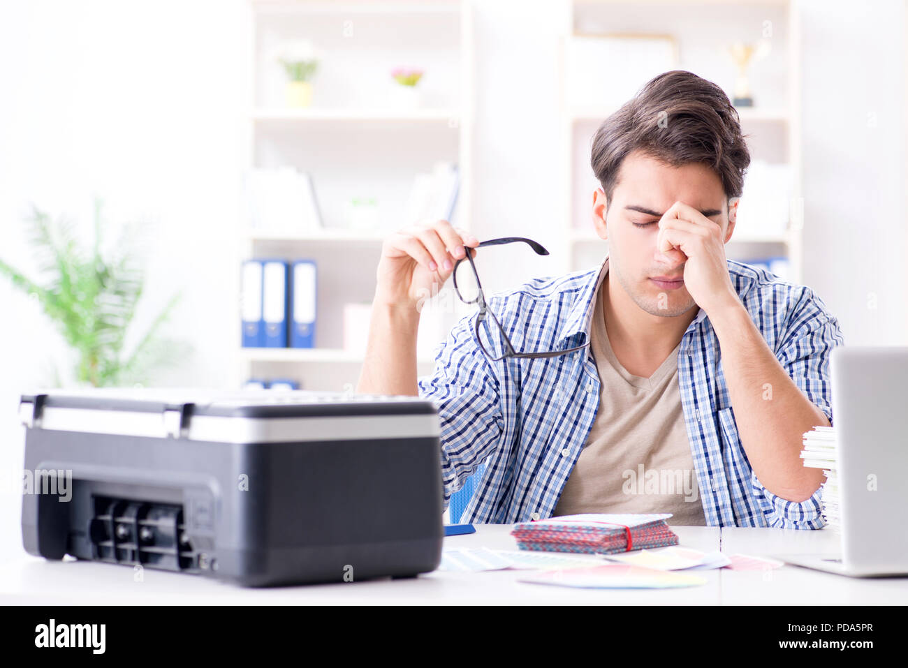 Young man employee working at copying machine in the office Stock Photo ...