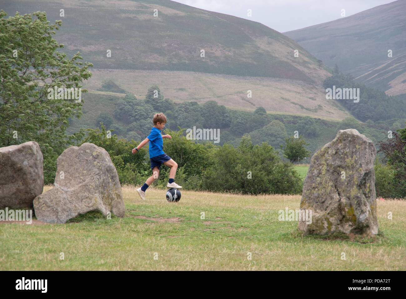 Children playing football and soccer using stones for goal posts with ...