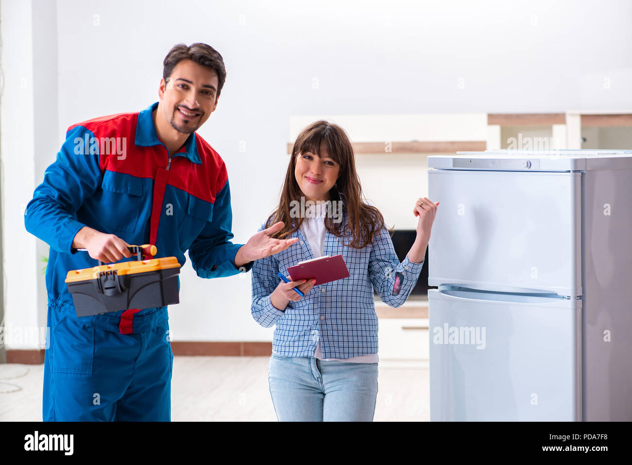 Man repairing fridge with customer Stock Photo - Alamy