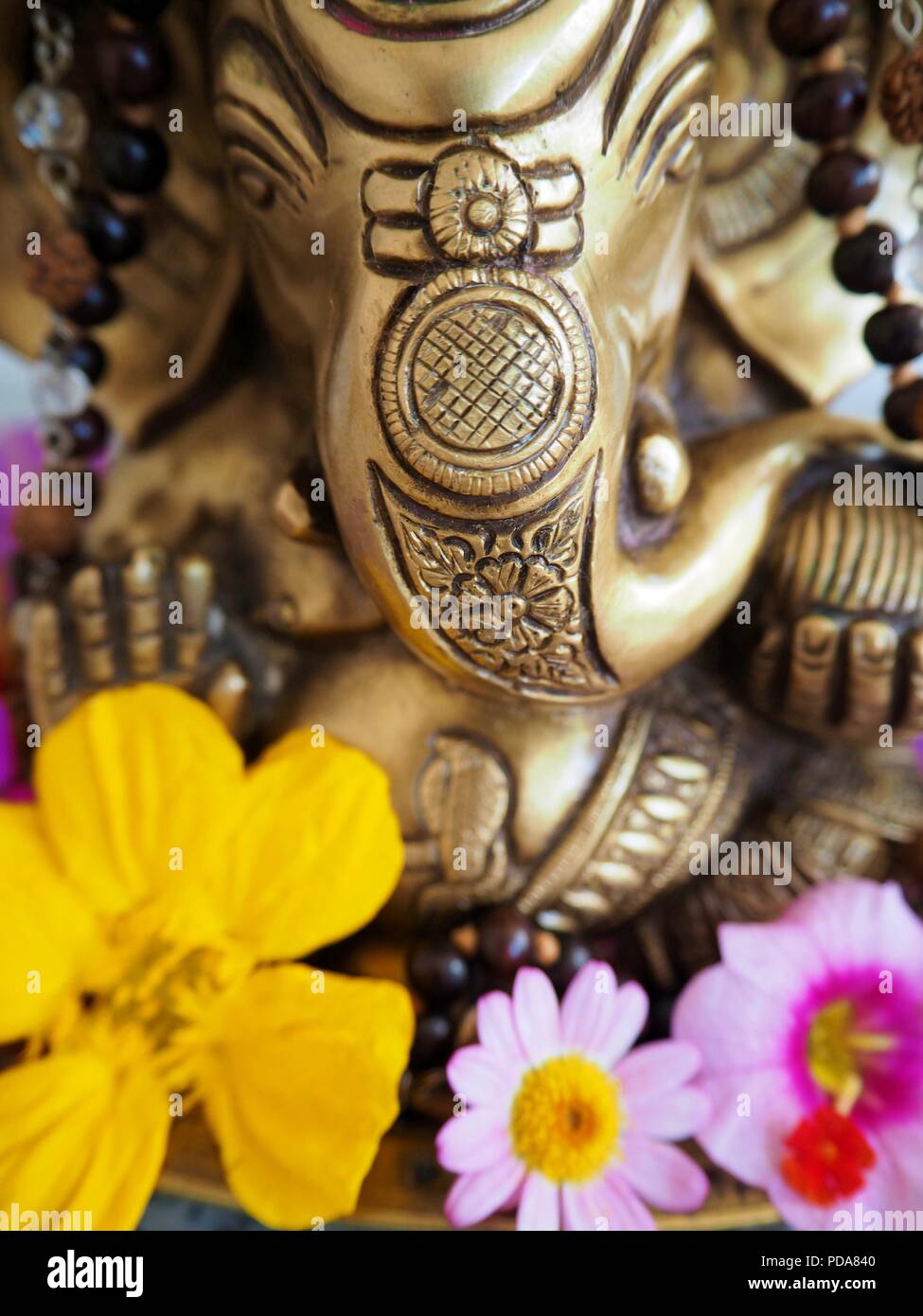 Hindu God Ganesha is covered with coloured flowers on an altar for a ...