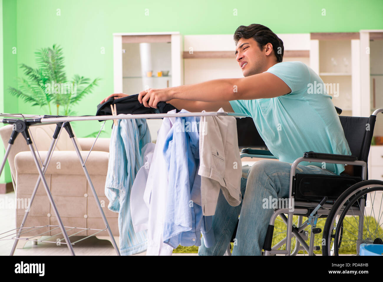 Disabled man on wheelchair doing laundry Stock Photo - Alamy
