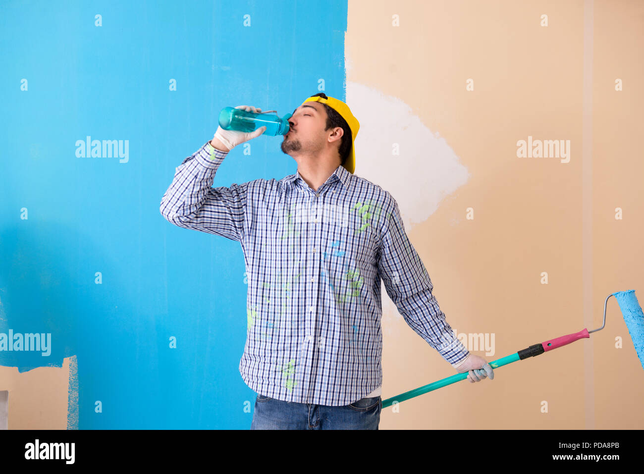 Painter man painting the wall at home Stock Photo - Alamy