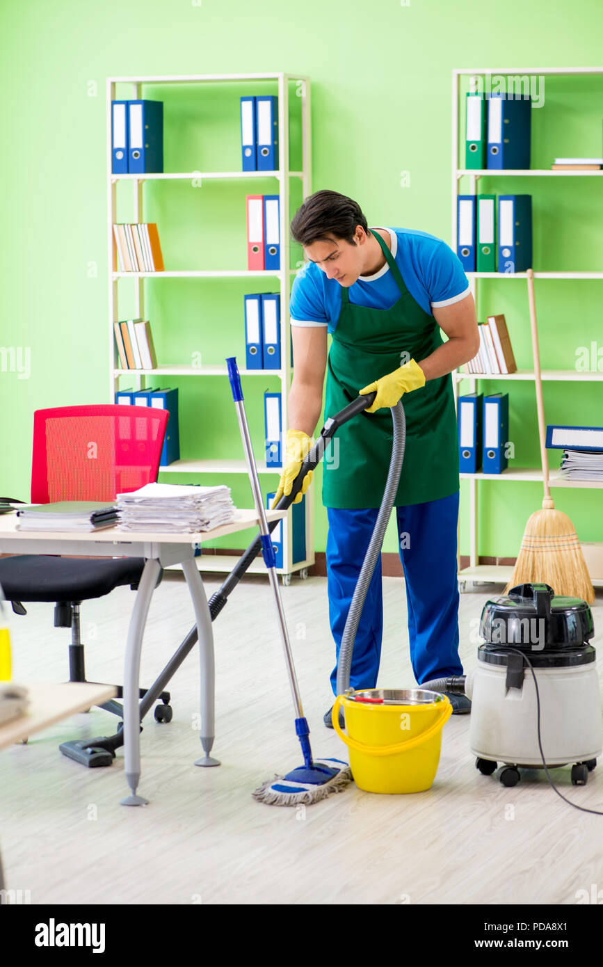 Handsome man cleaning office with vacuum cleaner Stock Photo - Alamy