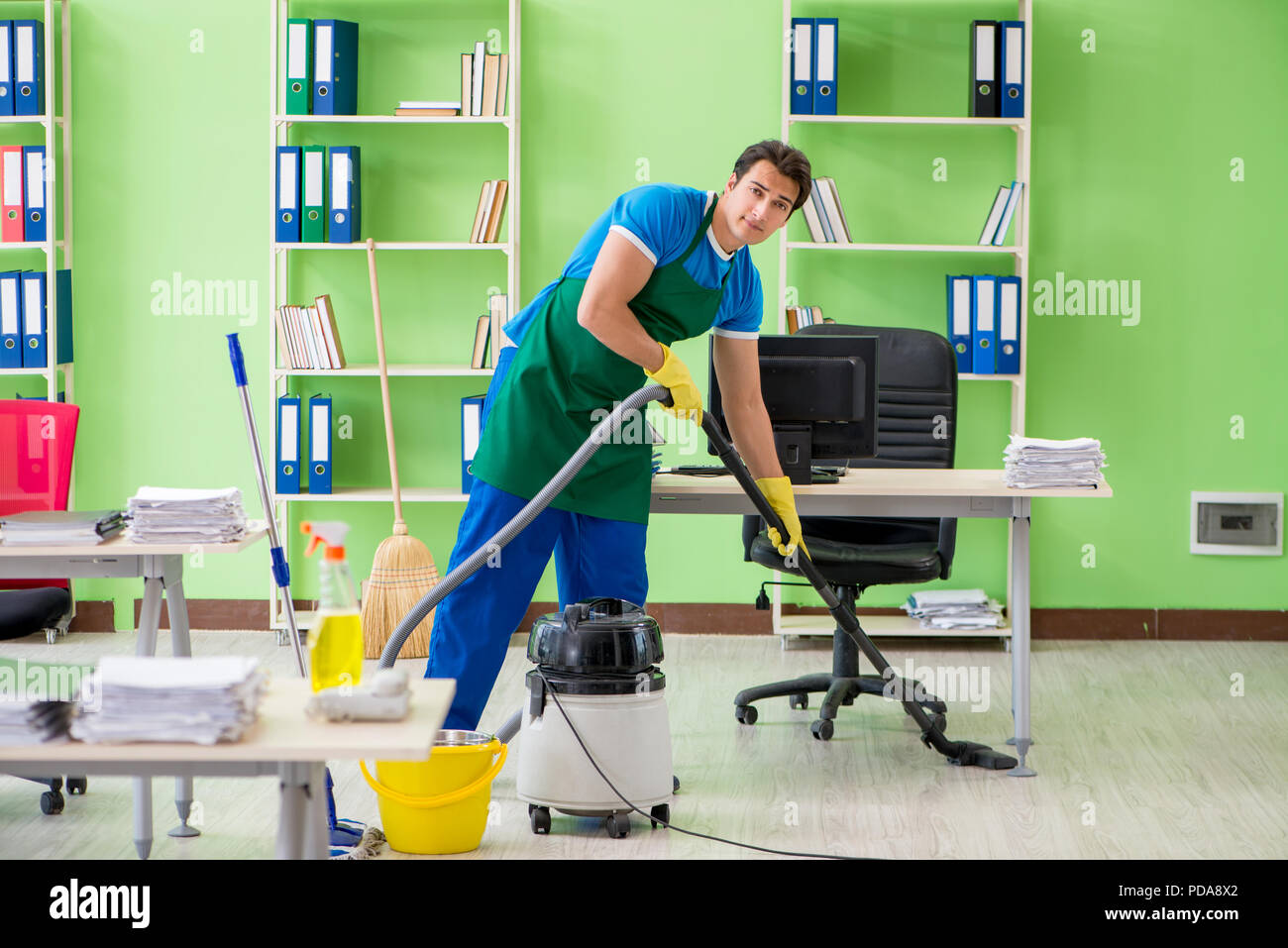 Handsome man cleaning office with vacuum cleaner Stock Photo - Alamy
